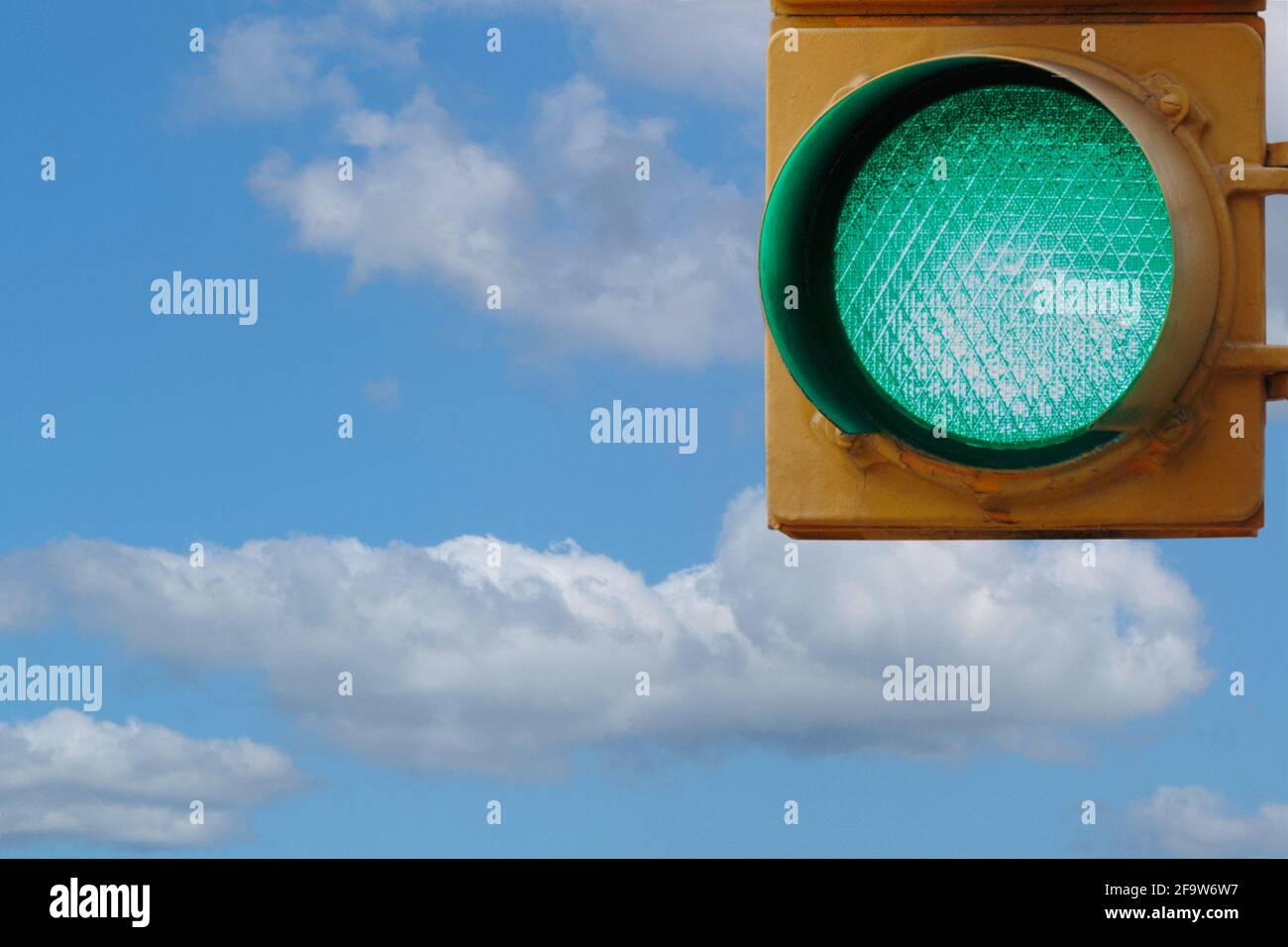 green traffic light against a blue sky with clouds with copy space ...