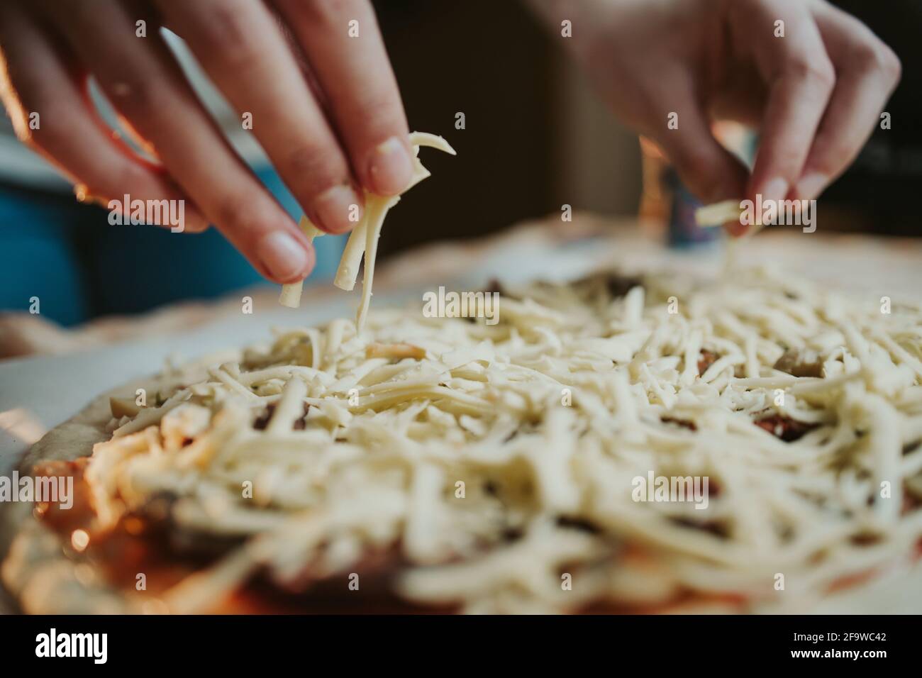 Person putting cheese on the homemade pizza Stock Photo - Alamy