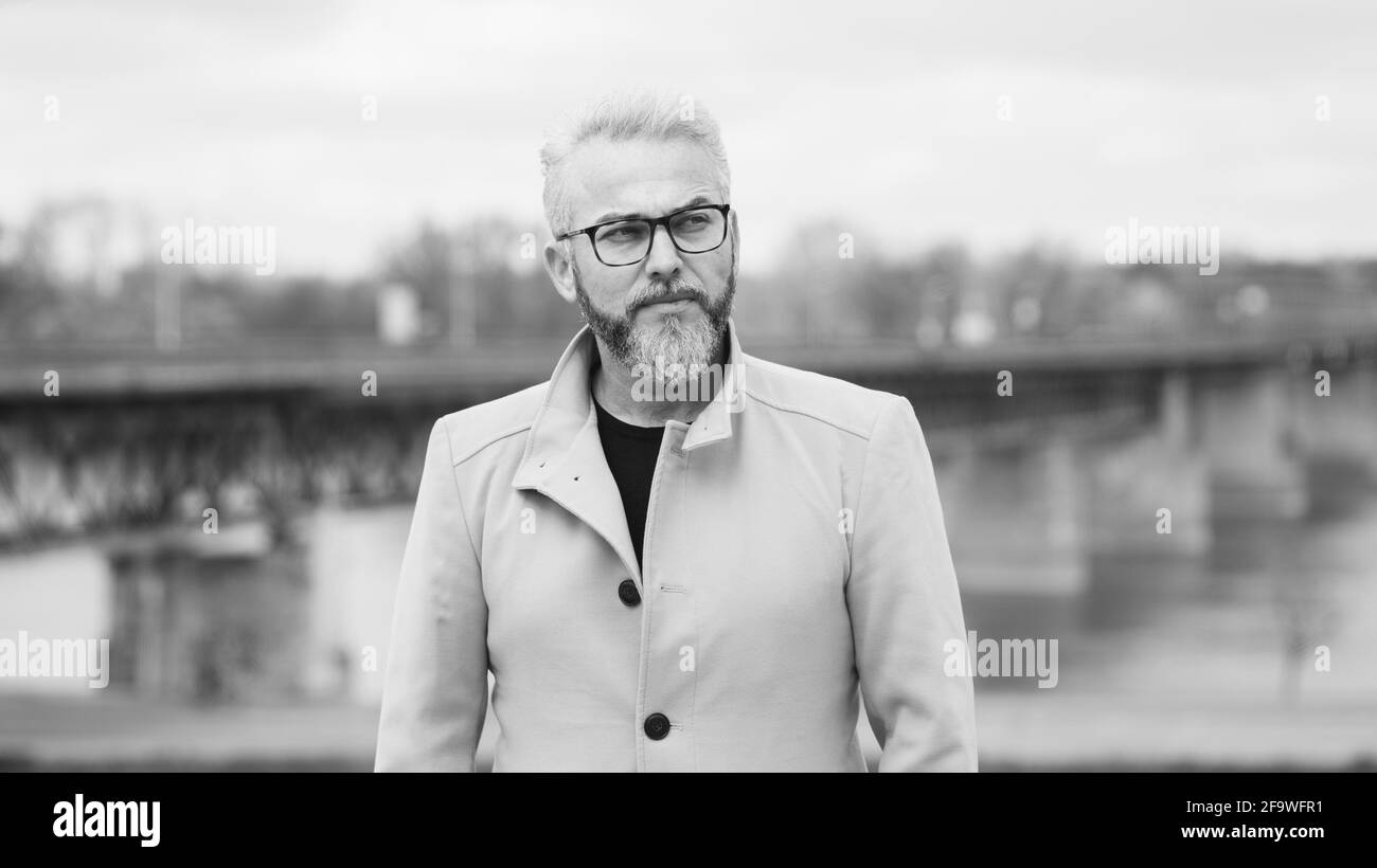 Grayscale of a confident man with gray hair wearing a stylish brown ...