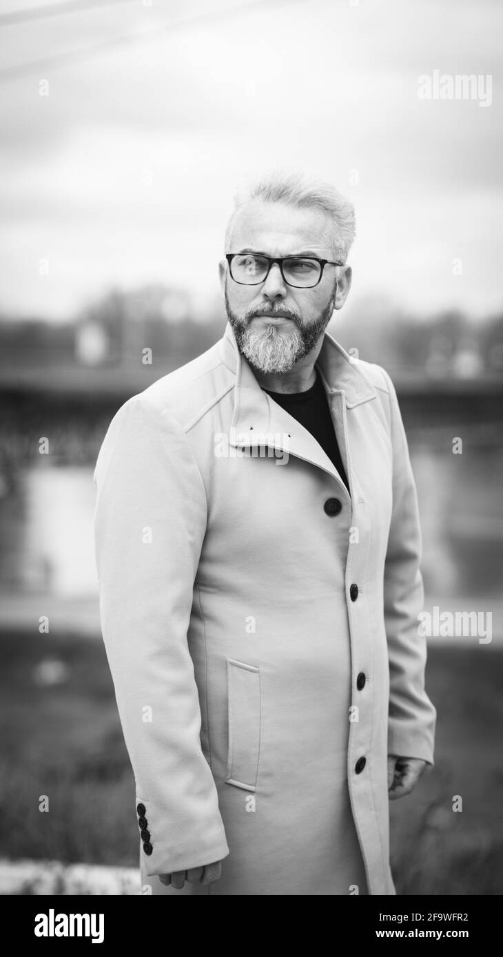 Grayscale of a confident man with gray hair wearing a stylish brown ...