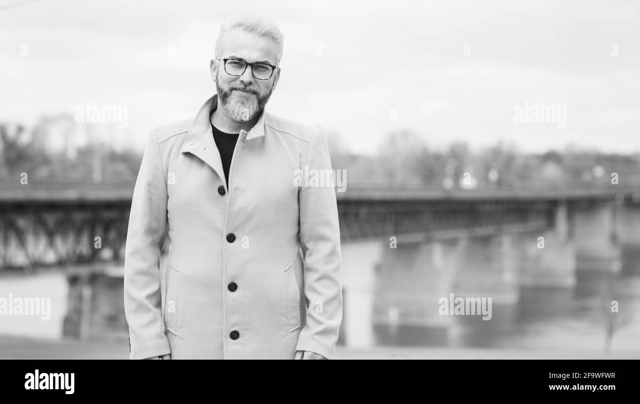 Grayscale of a confident man with gray hair wearing a stylish brown ...
