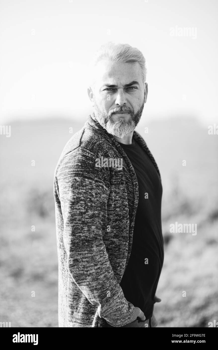 Grayscale shot of a confident man with gray hair posing at camera with ...