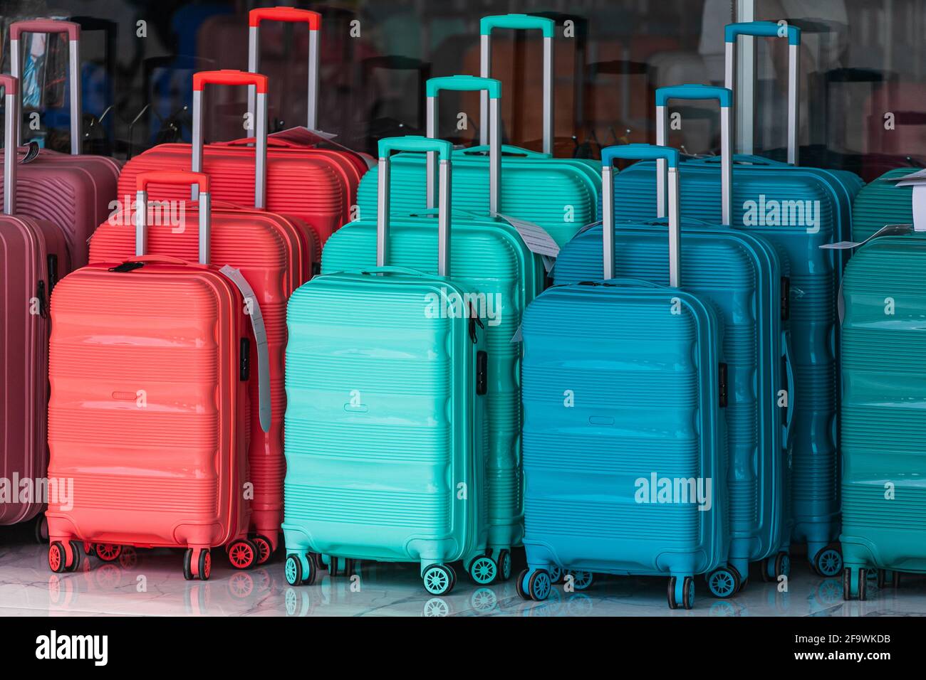 Bright blue, red, green rows of suitcases with extended handles and ...