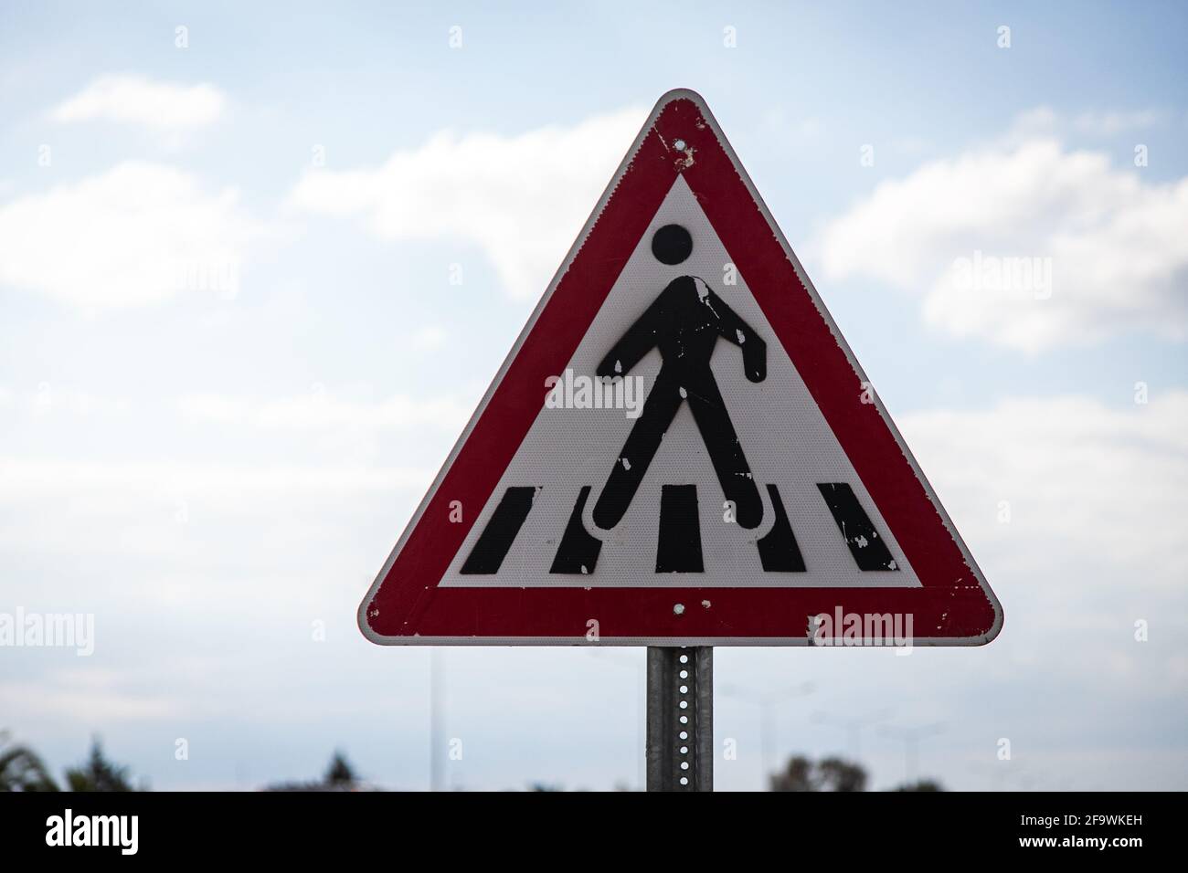 pedestrian crossing road sign in a triangular shape on a blue sky ...