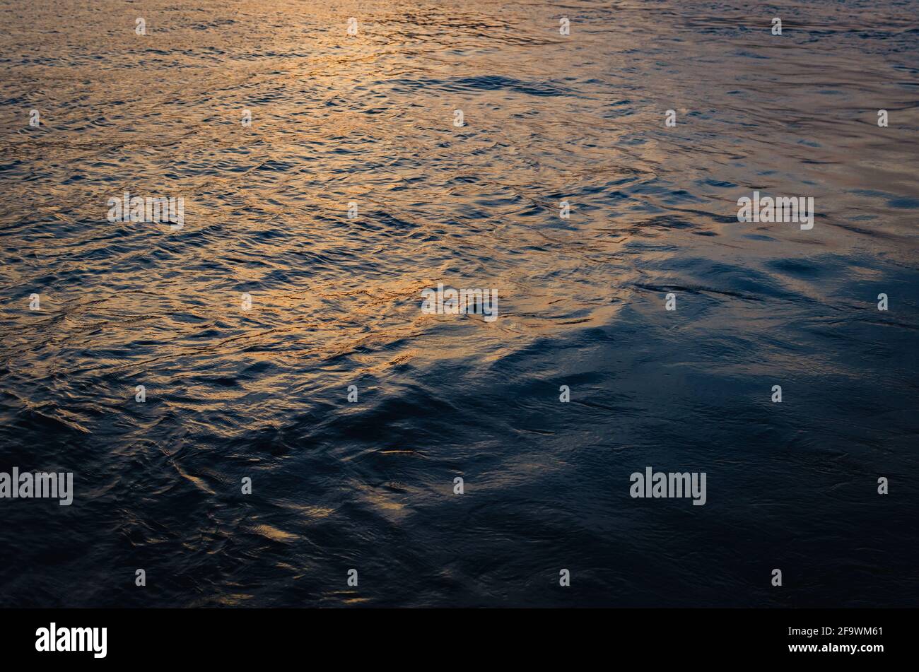 Wave surface of dark blue river with sun light on water when sunset ...