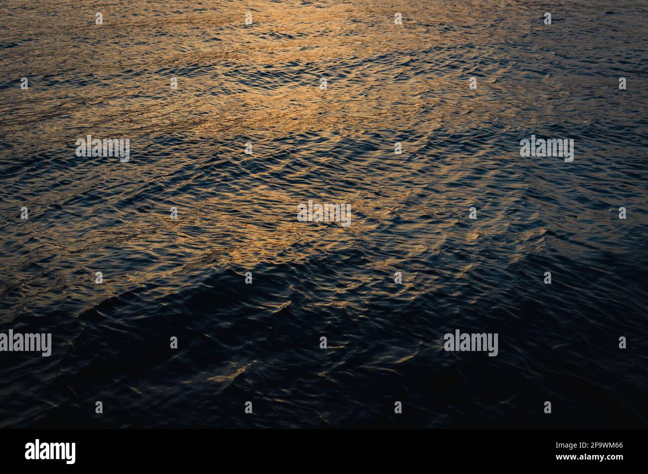 Wave surface of dark blue river with sun light on water when sunset ...