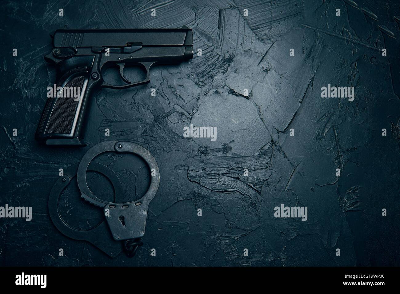 Top view of hand gun and handcuffs on green table. Pistol for a law ...