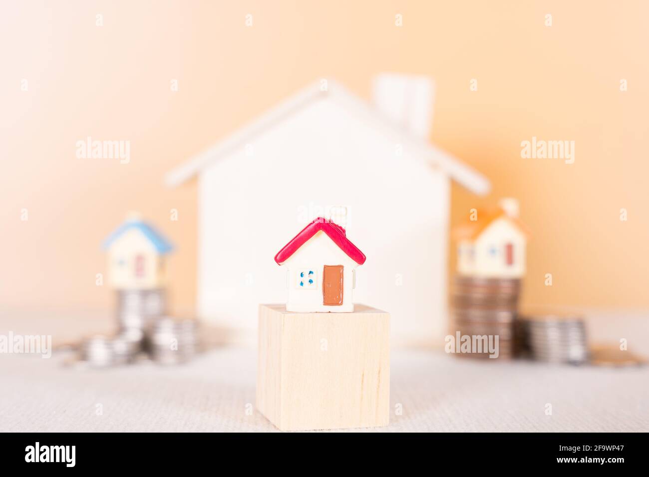 House on wooden block and stack coins isolated orange background ...