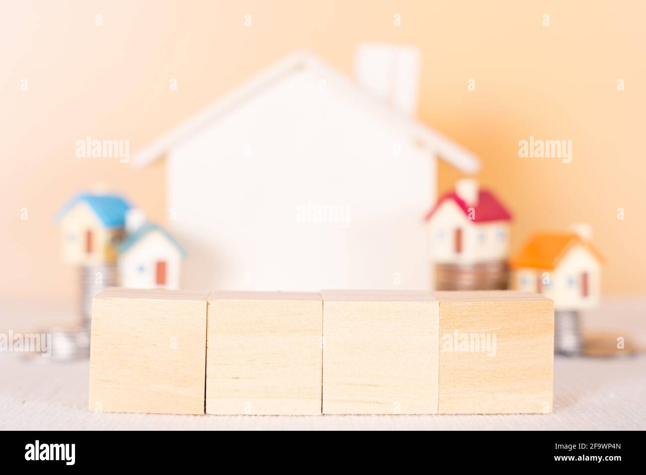 Wooden block and house on stack coins isolated orange background ...