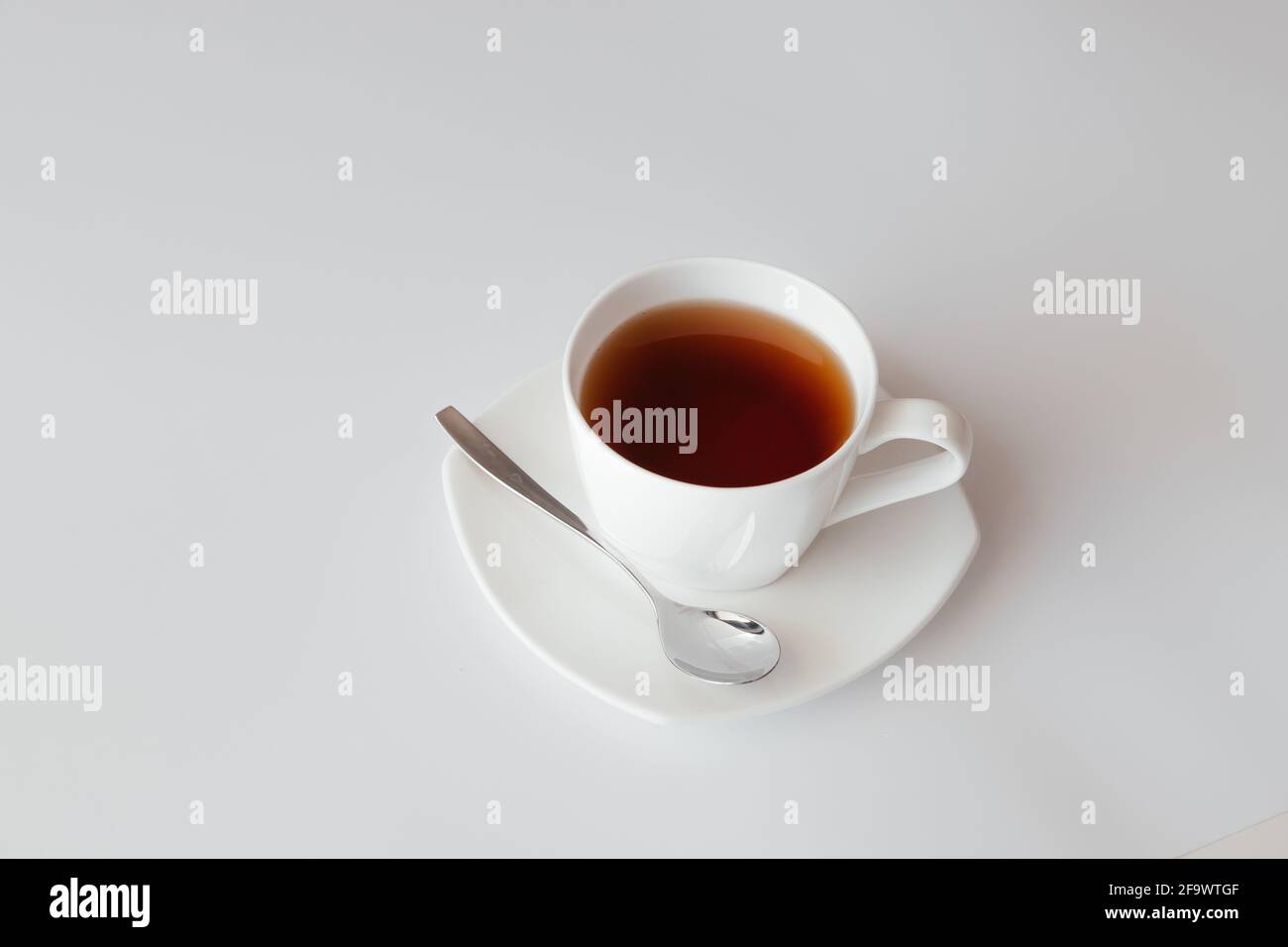 One white cup of tea with saucer and spoon on white background. Top ...
