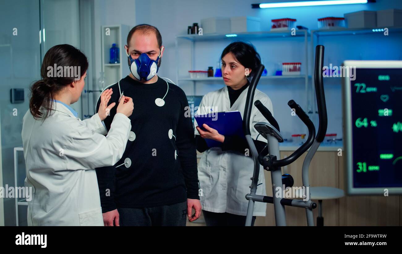 Scientist researcher preparing man patient for endurance test attaching ...