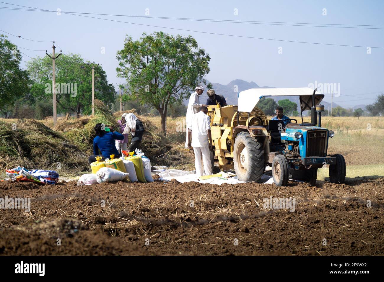farmers in traditional clothes loading grain into a tractor where it is ...