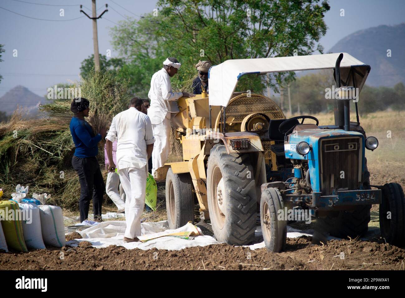 farmers in traditional clothes loading grain into a tractor where it is ...