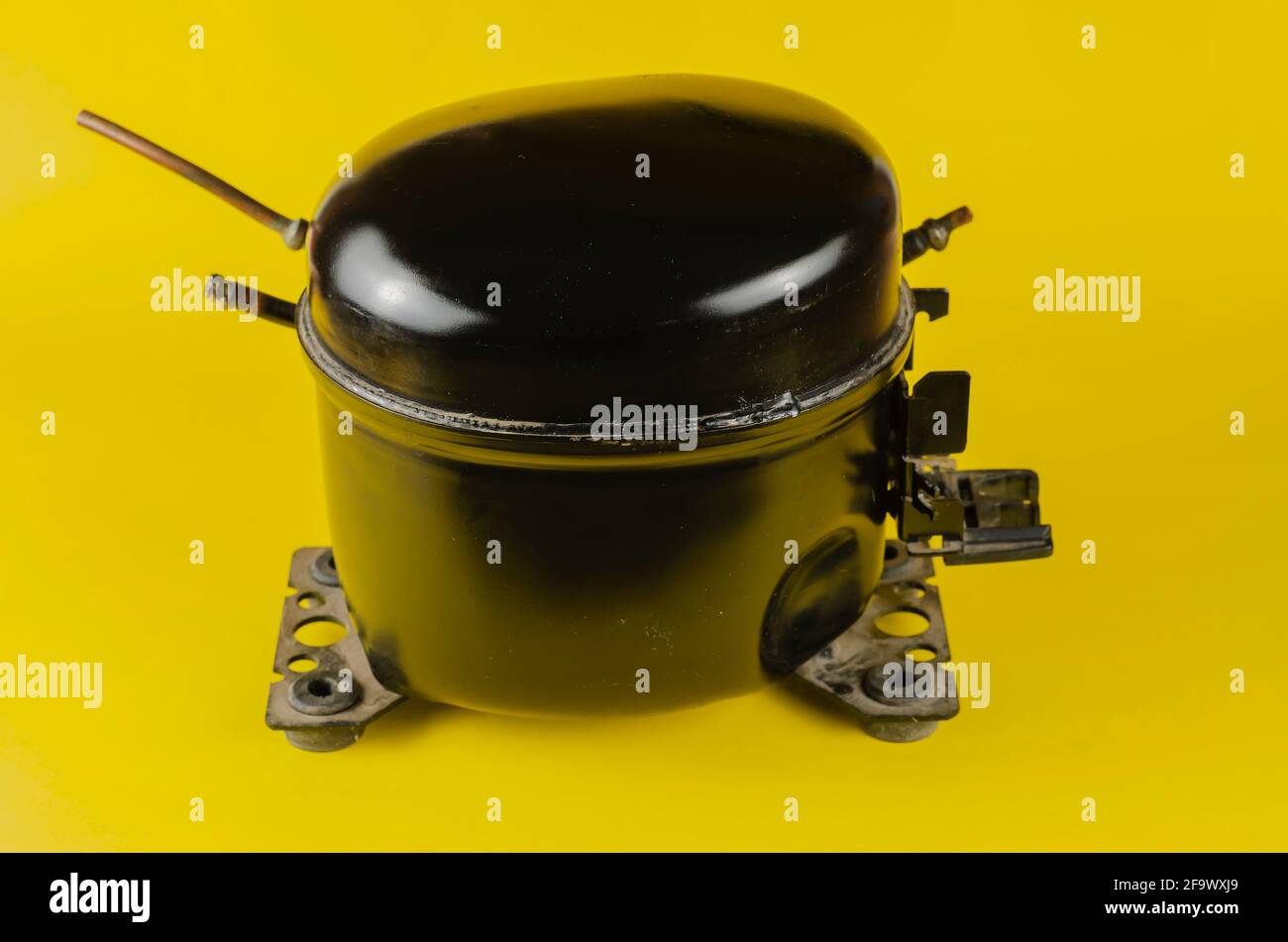 Black refrigerator motor-compressor on yellow background. Old hermetic ...