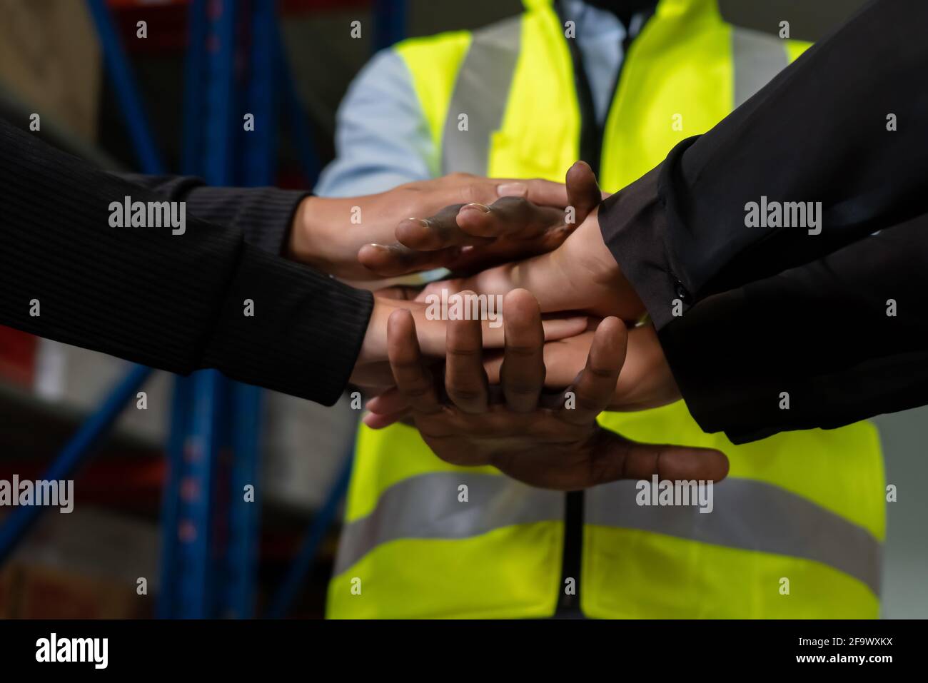 Factory workers stacking hands together in warehouse or storehouse ...