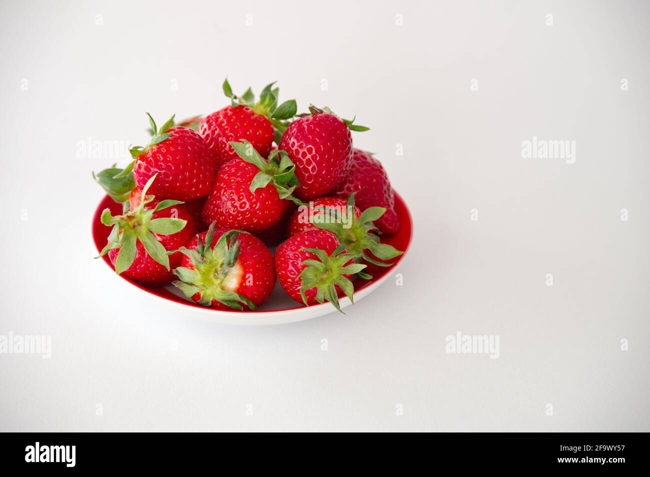 Strawberries on a plate against white background Stock Photo - Alamy