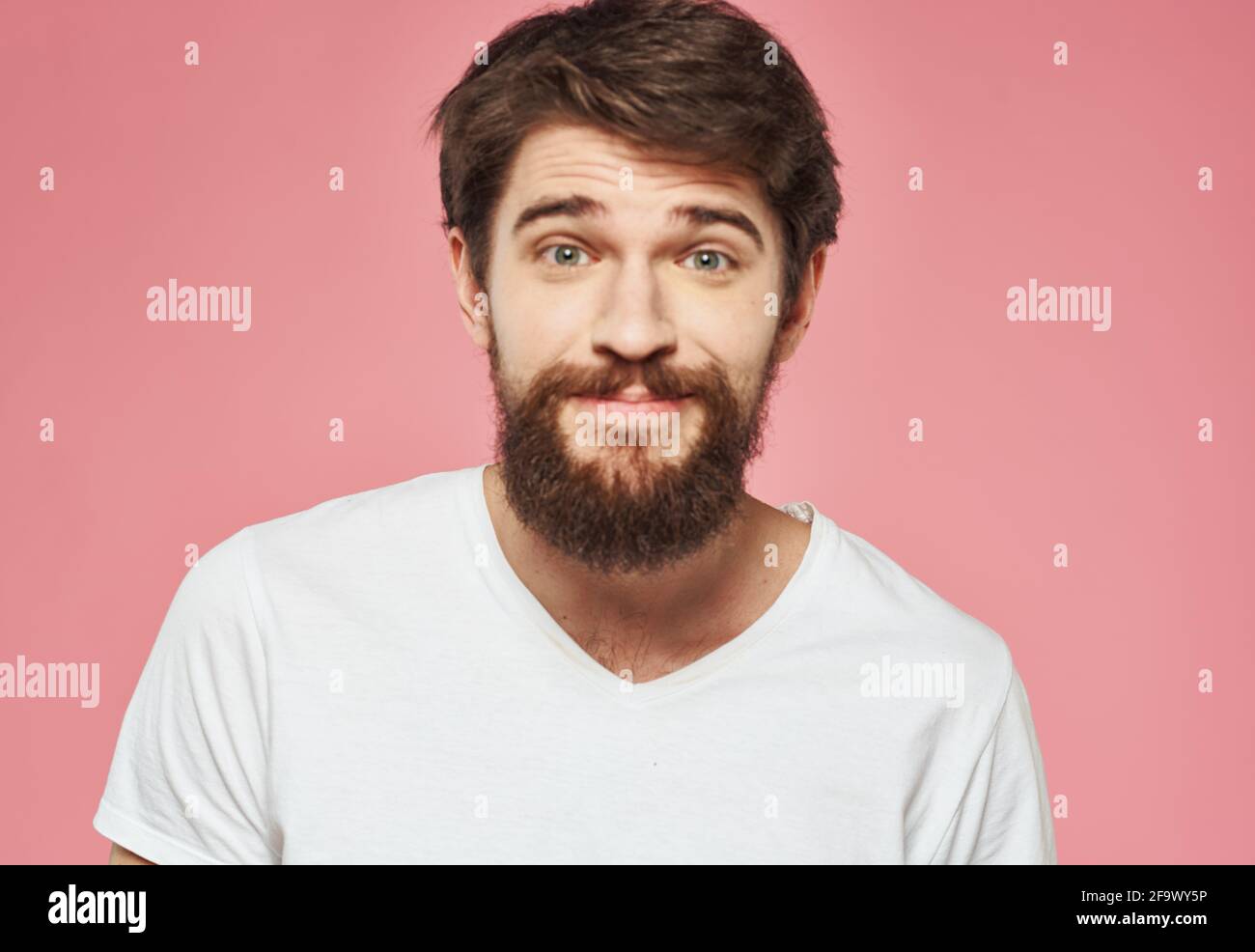 Portrait of a happy man with a beard on a pink background in a white T ...
