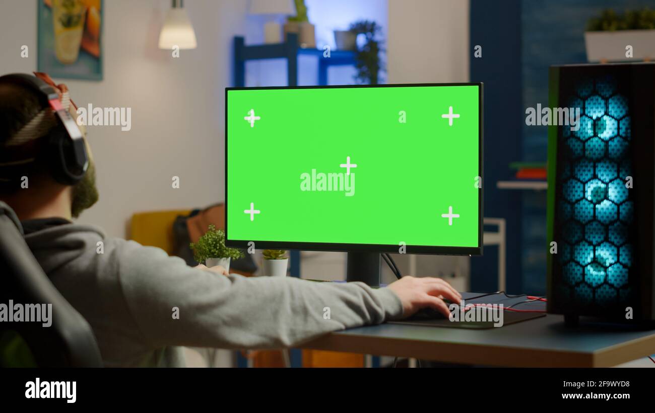 Pro gamer streaming video games with green screen mock-up display in ...