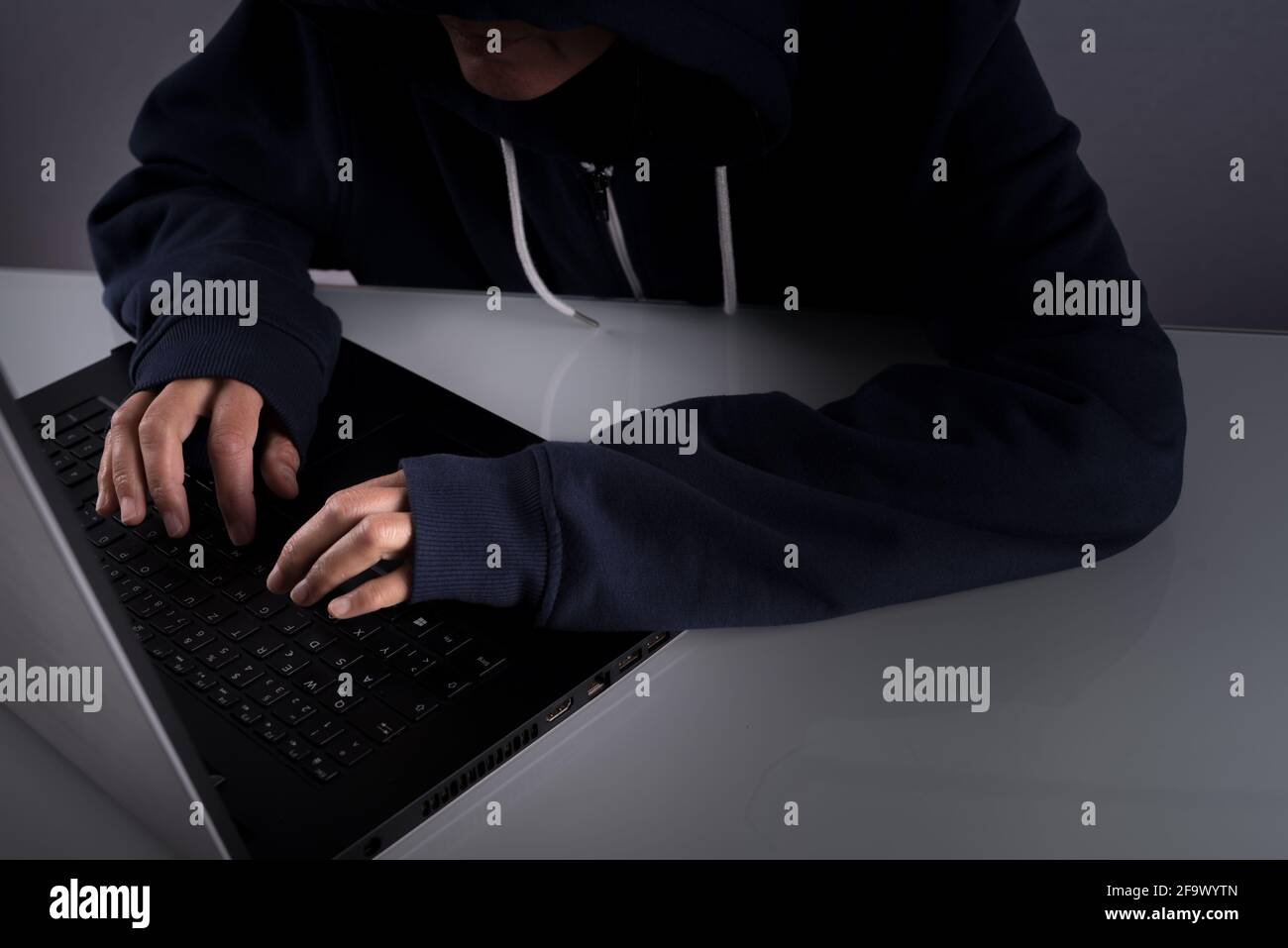 Closeup of a hacker typing and working on his laptop Stock Photo - Alamy