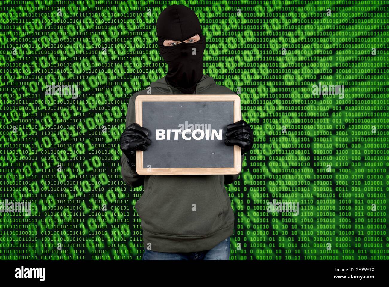 Hacker holding a blackboard with BITCOIN written on it, in front of a ...