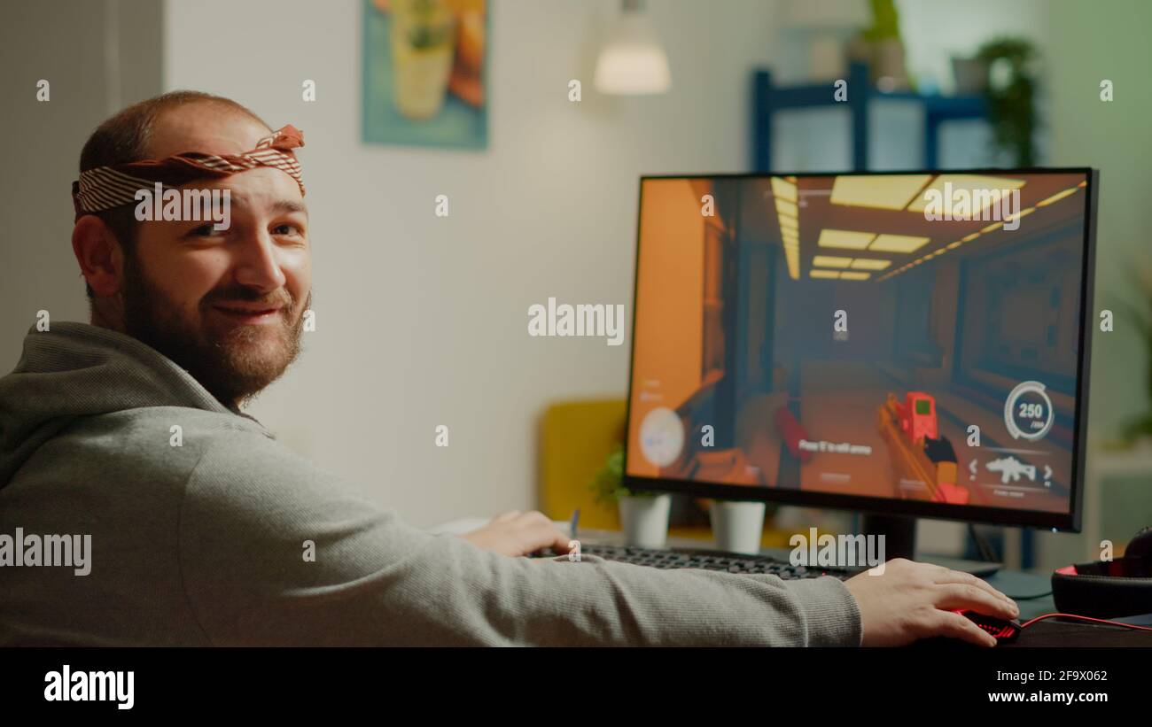 Pro man gamer turning head looking at camera smiling playing FPS ...