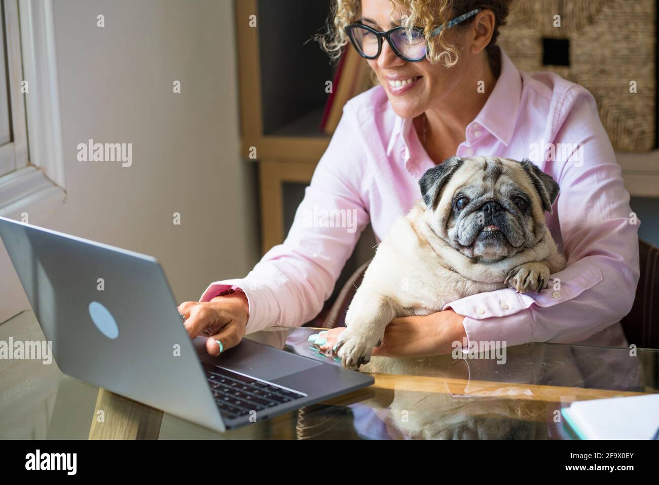 Adult pretty young woman work at laptop computer and hug her adorable ...