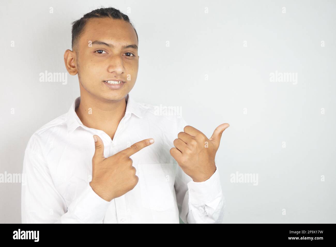 Young South Asian guy wearing a white shirt pointing to the left ...