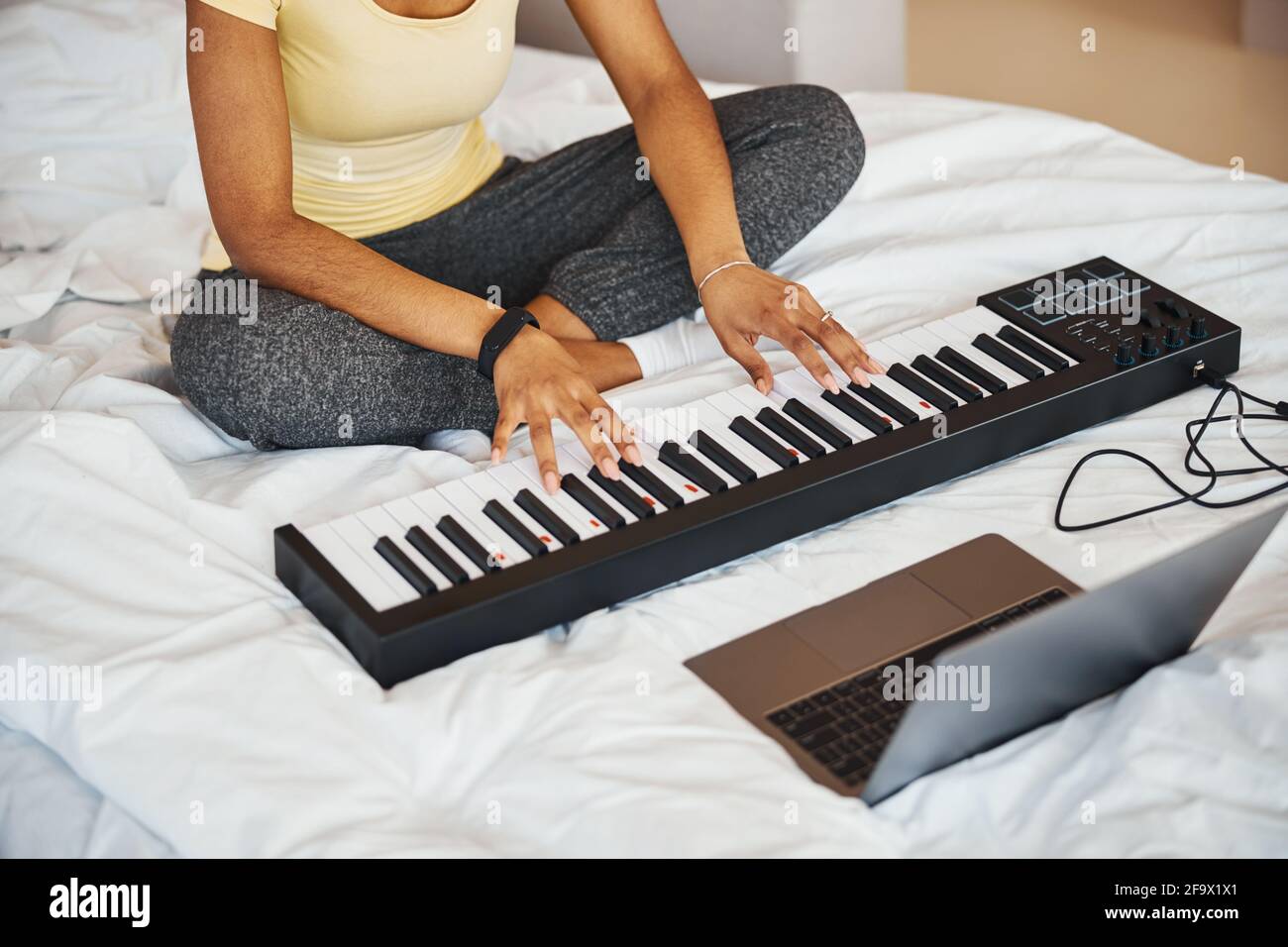 Female musician playing synthesizer and using notebook at home Stock ...