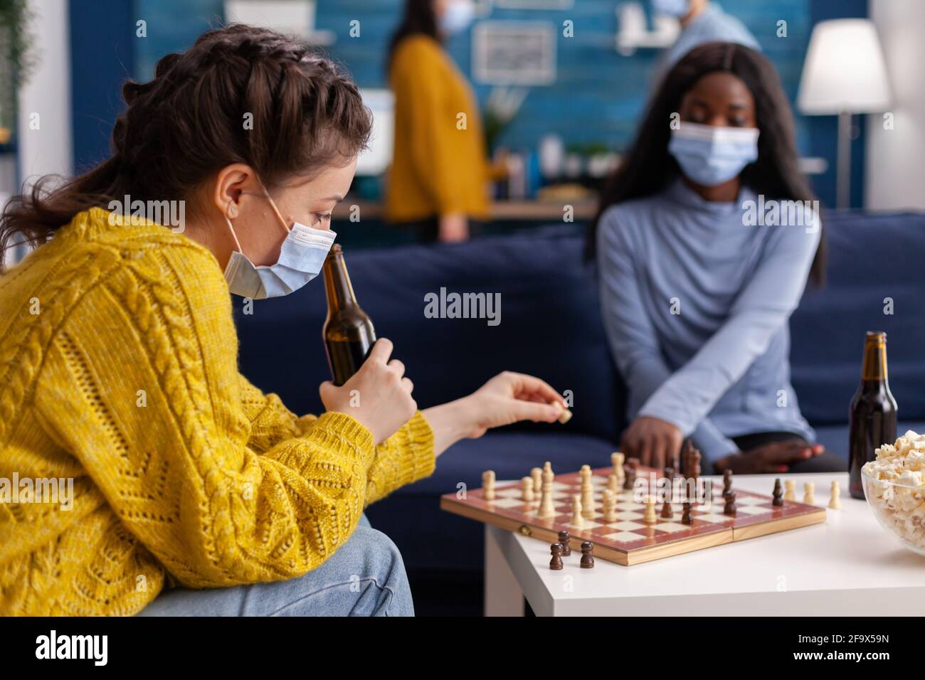 Friends with protection masks relaxing playing chess while drinking ...