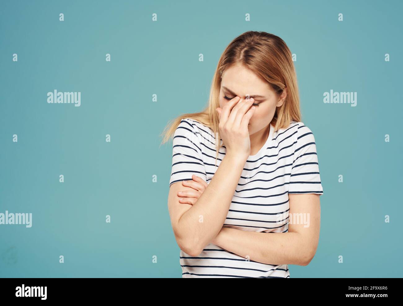 Upset woman touches her face with her hands on a blue background close ...
