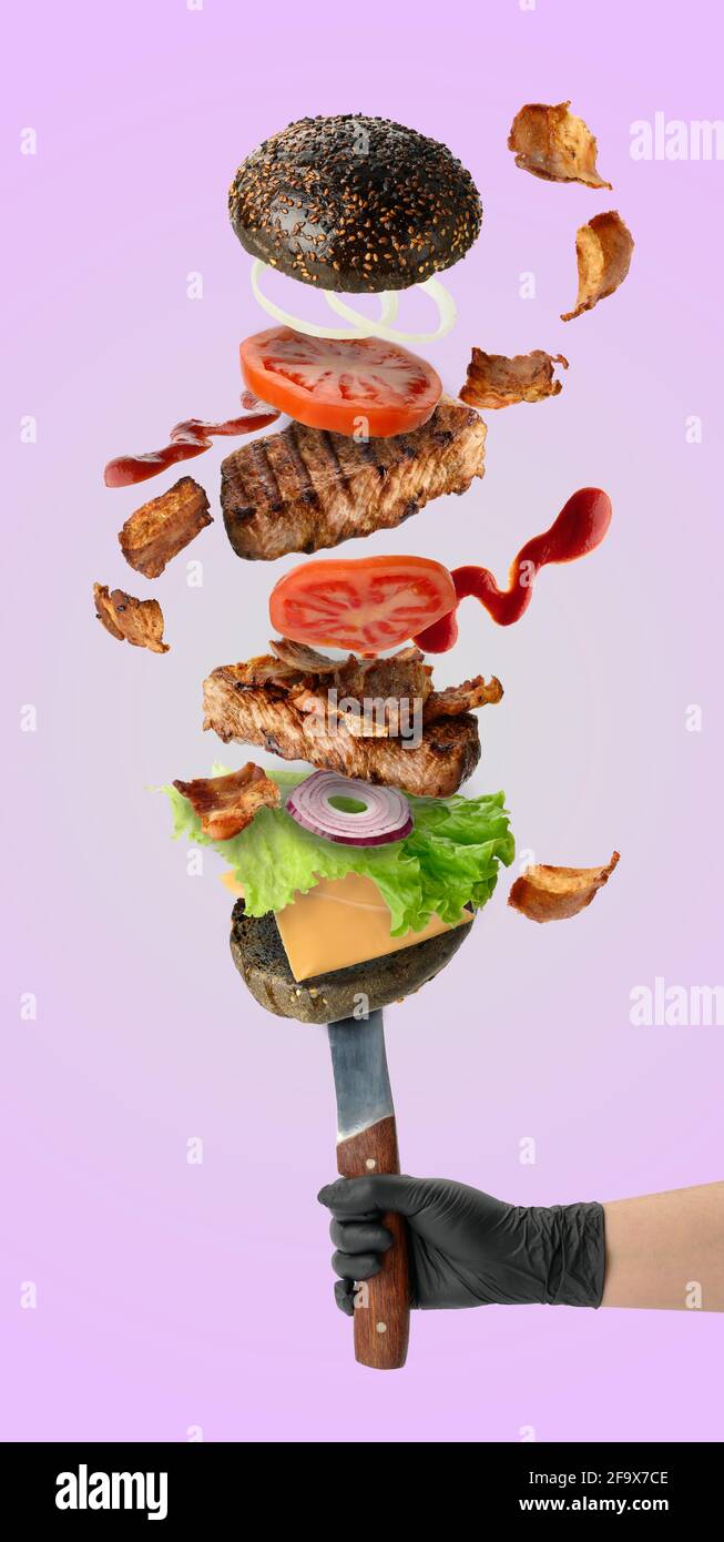 layers of large cheeseburger black bun with sesame seeds, beef fried ...