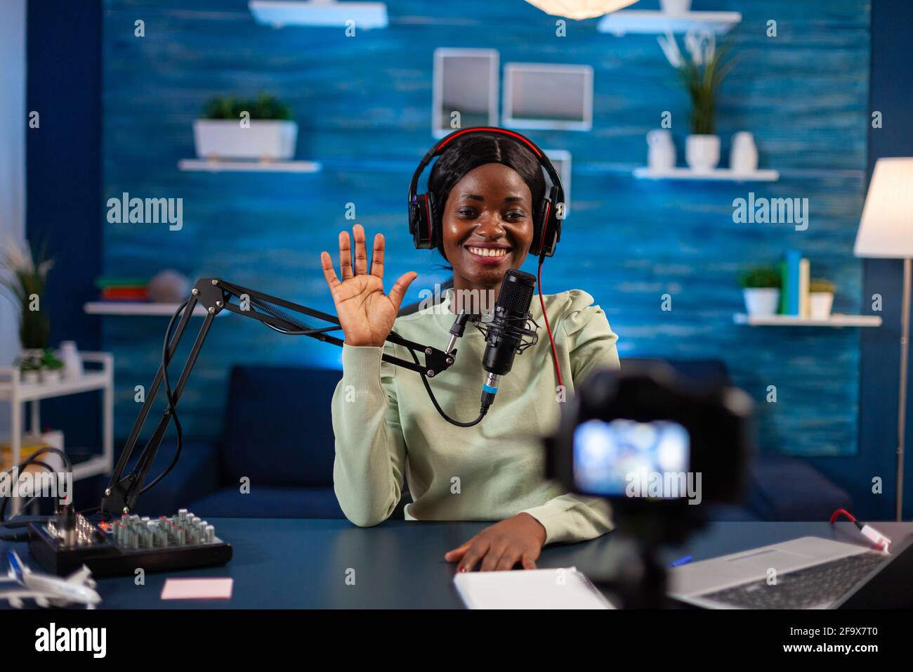 African blogger waving at audience while filming podcast. On-air ...