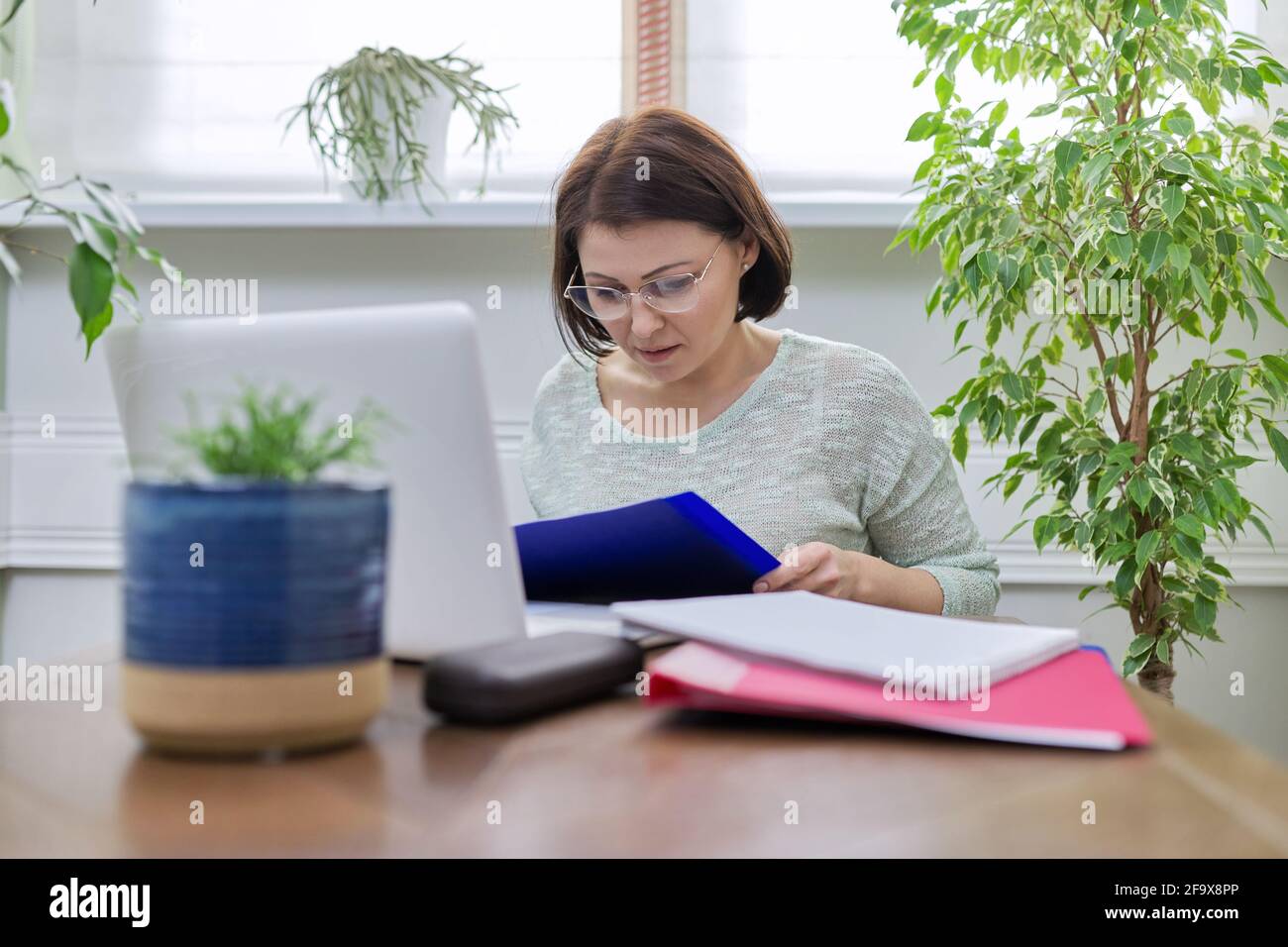 Female teacher teaching online, sitting at home at table with laptop ...