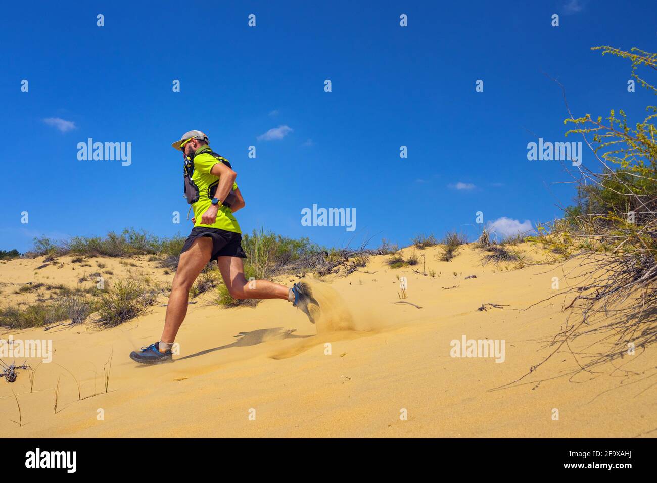 Athlete running off-road in the wild. A man in shorts and a T-shirt is ...