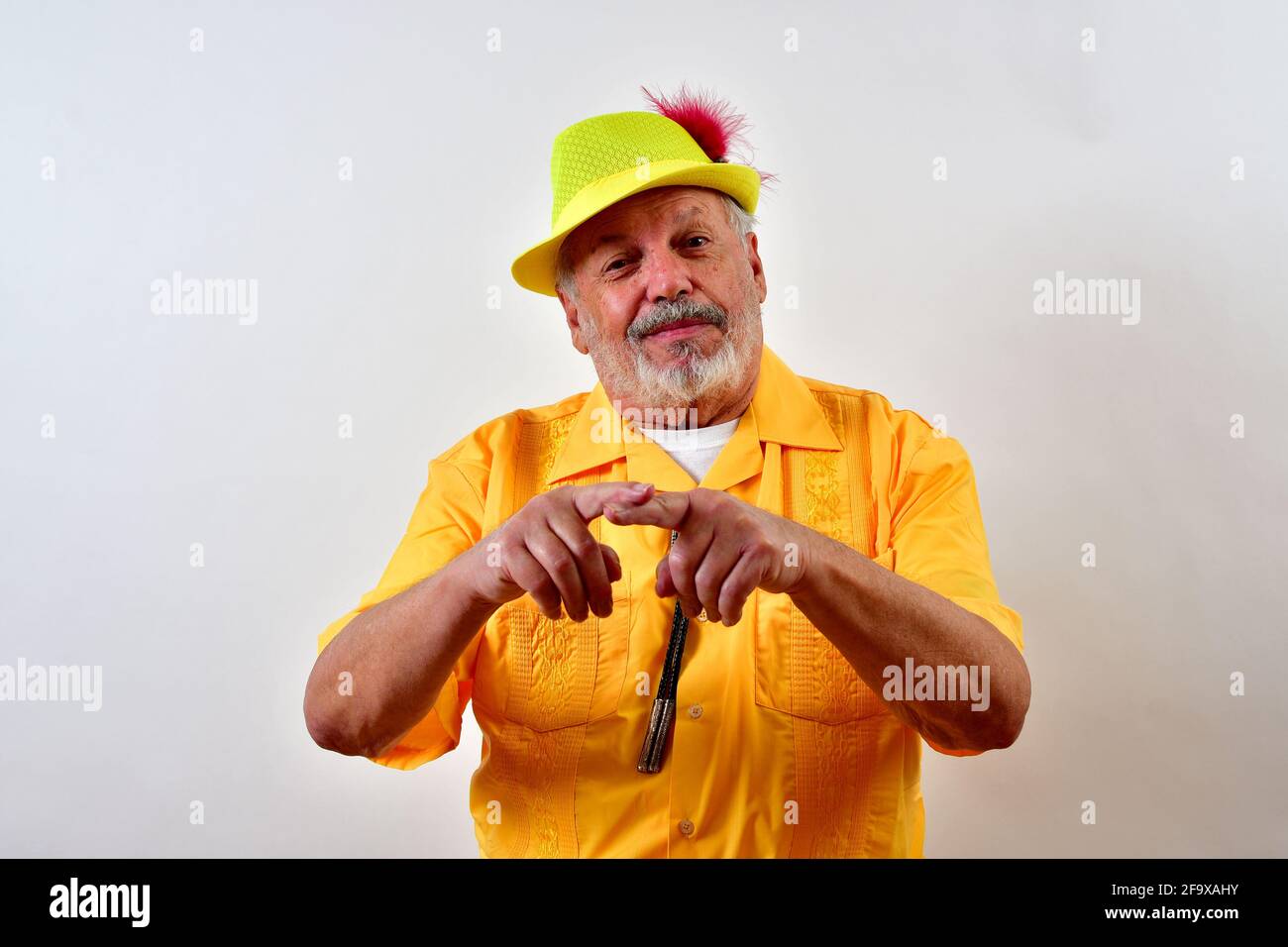 Senior male in a cute yellow outfit doing the shame finger sign front ...