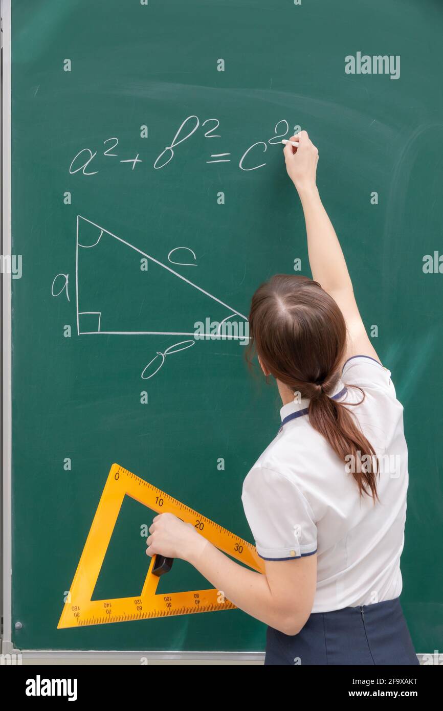 school teacher young woman in the class at the blackboard draws a ...