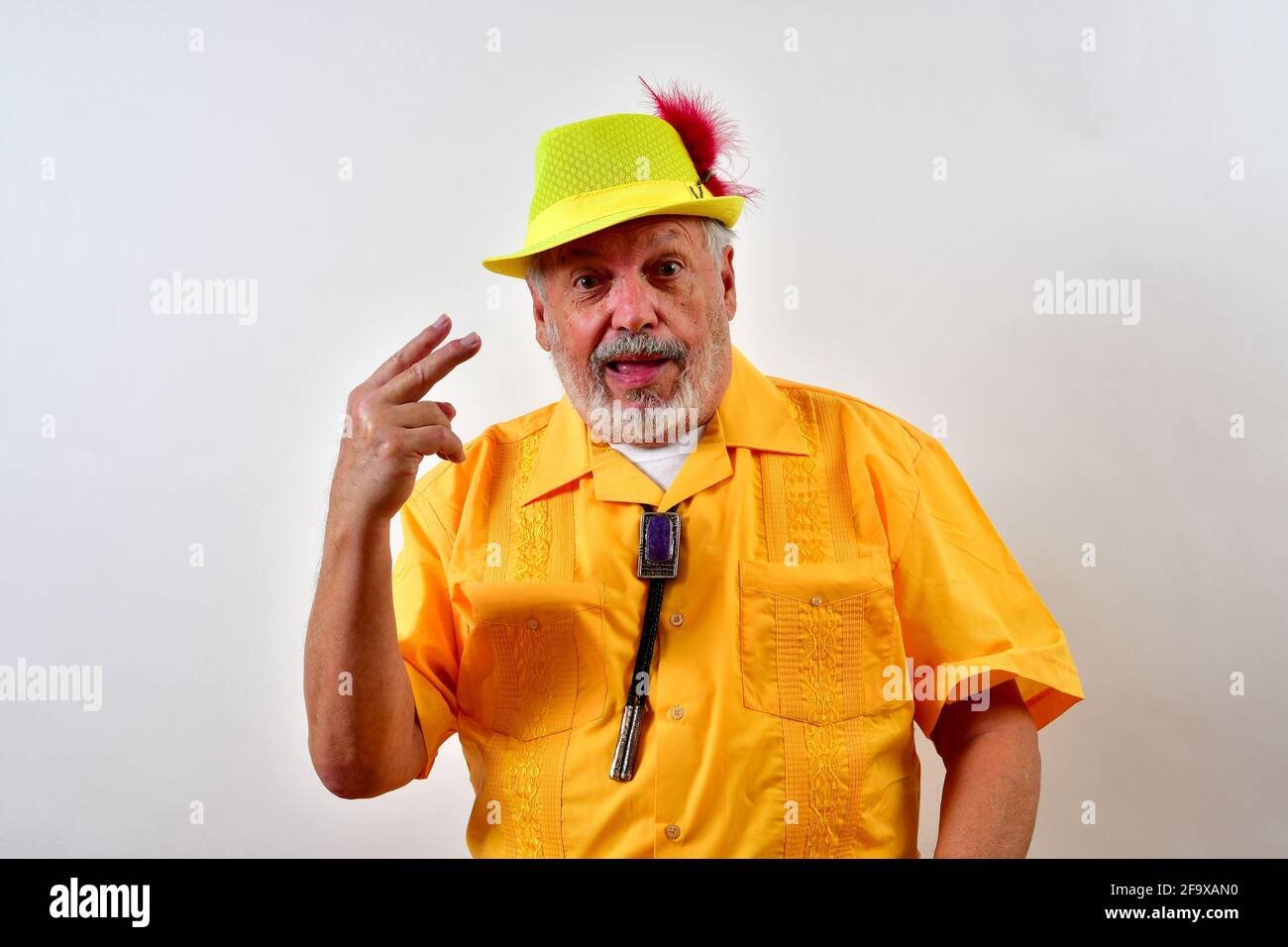 Senior male in a cute yellow outfit holding up two fingers front of a ...