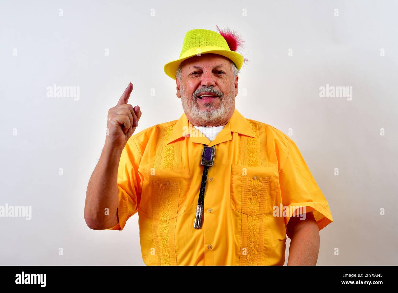 Senior male in a cute yellow outfit holding up one finger front of a ...