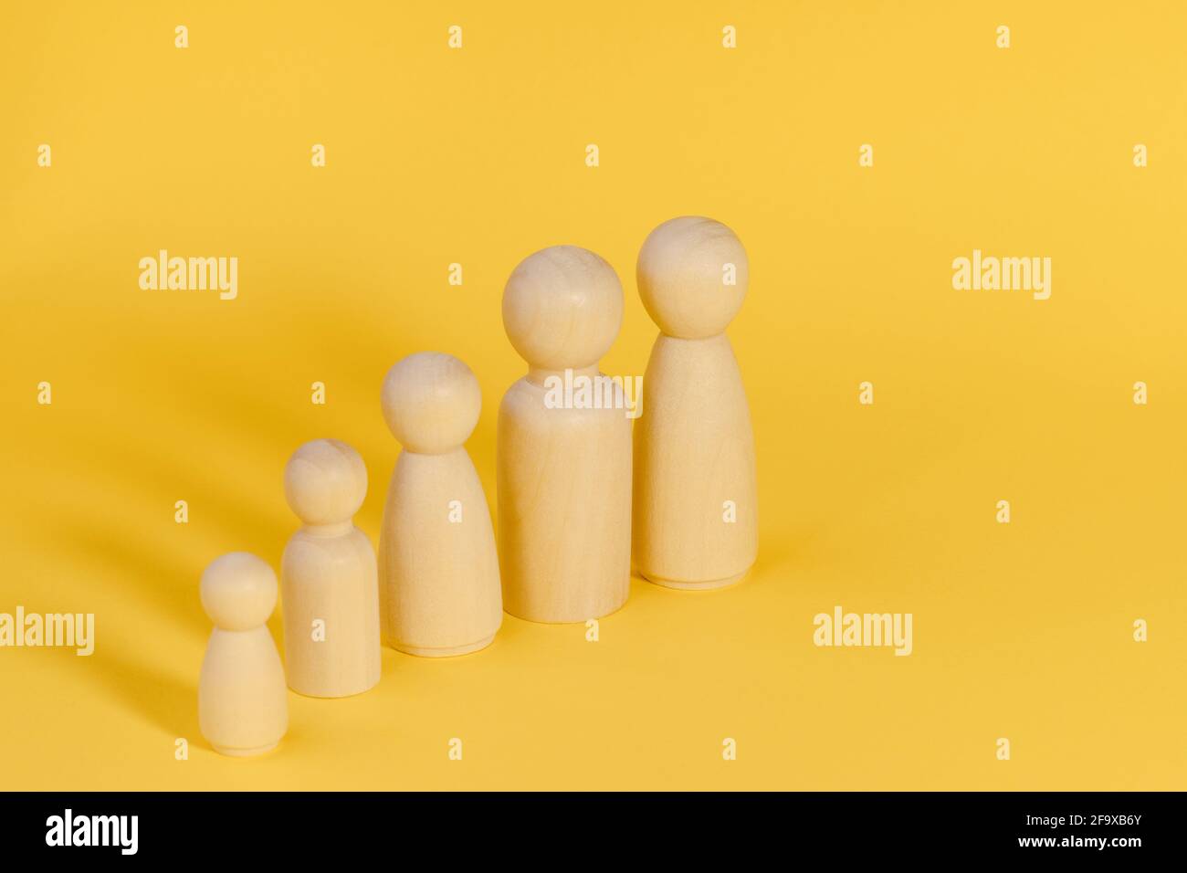 Family of five members made from wooden figurines on yellow background ...