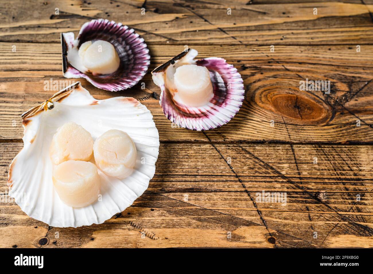 Raw seafood scallops meat on a shells. Wooden background. Top view ...