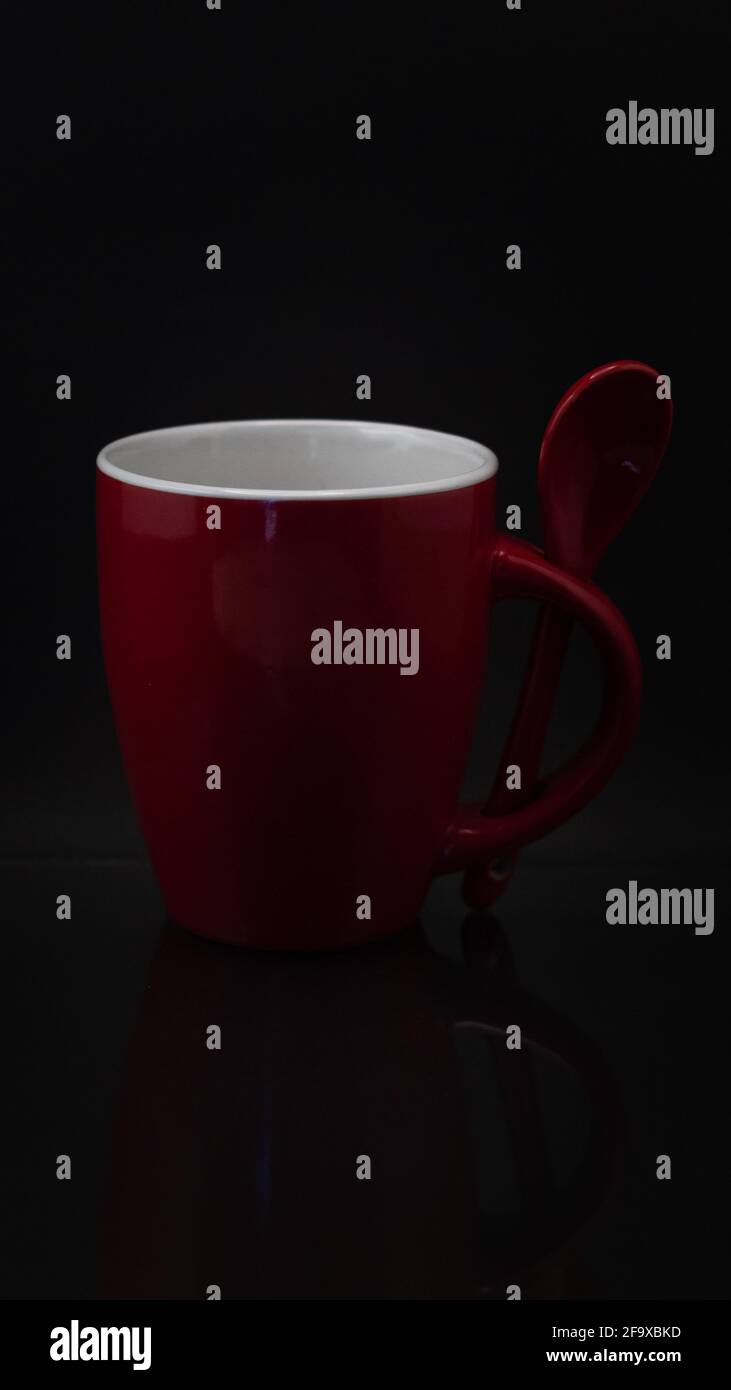 Closeup shot of a red mug with a spoon on a black background Stock ...