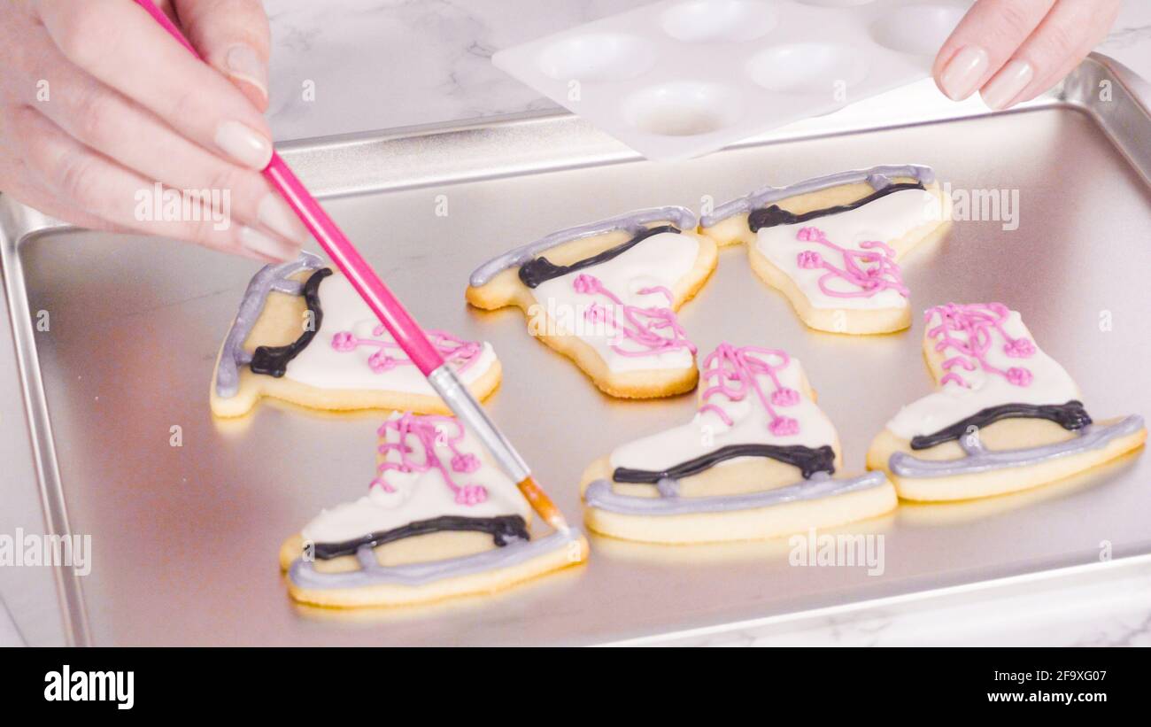 Brushing edible glitter on iced figure skate sugar cookies Stock Photo ...