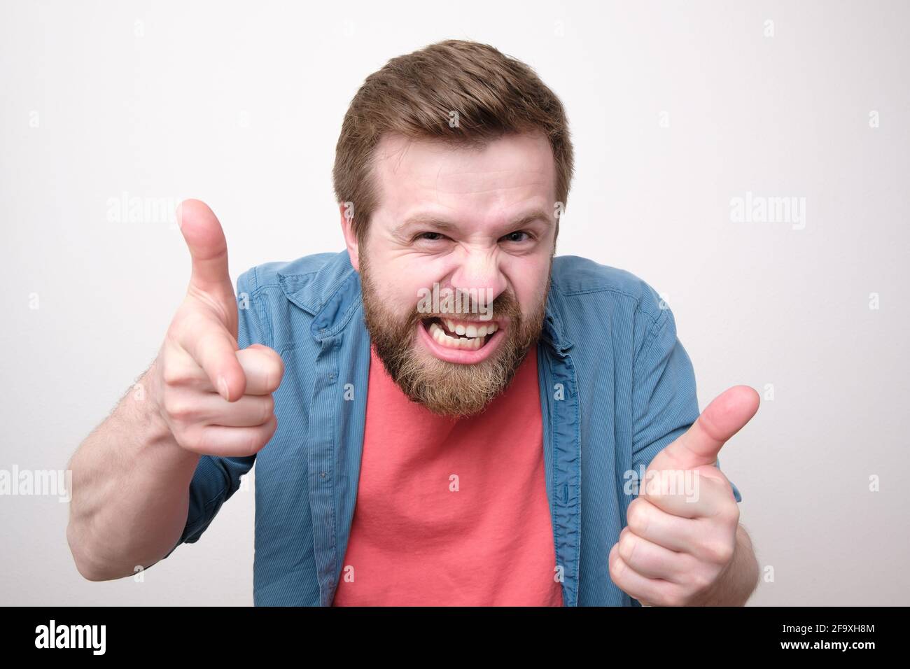 Strange bearded man makes a gesture with hands like it a gun and bares ...