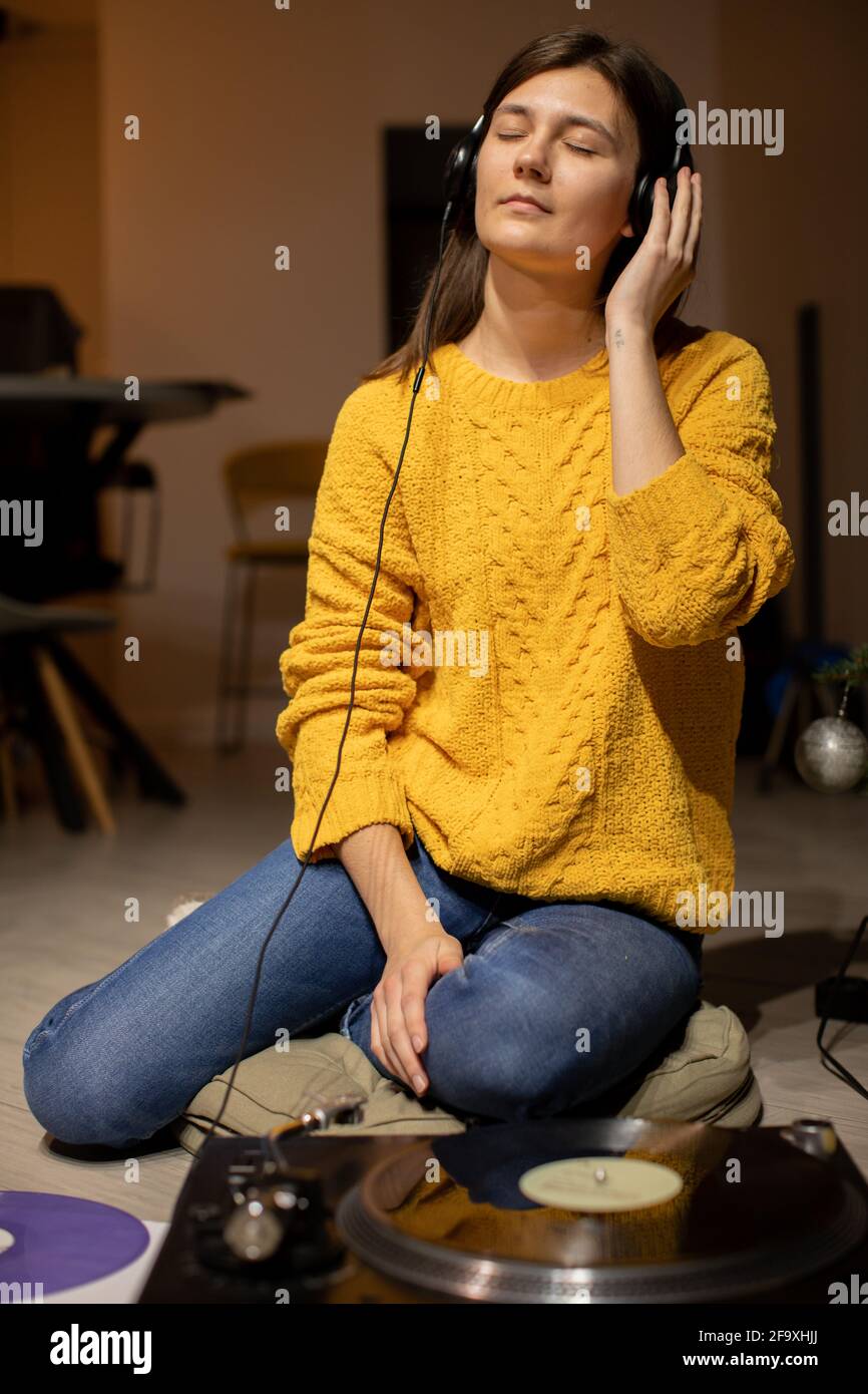 girl sitting on floor enjoys to music with headphones and analog ...