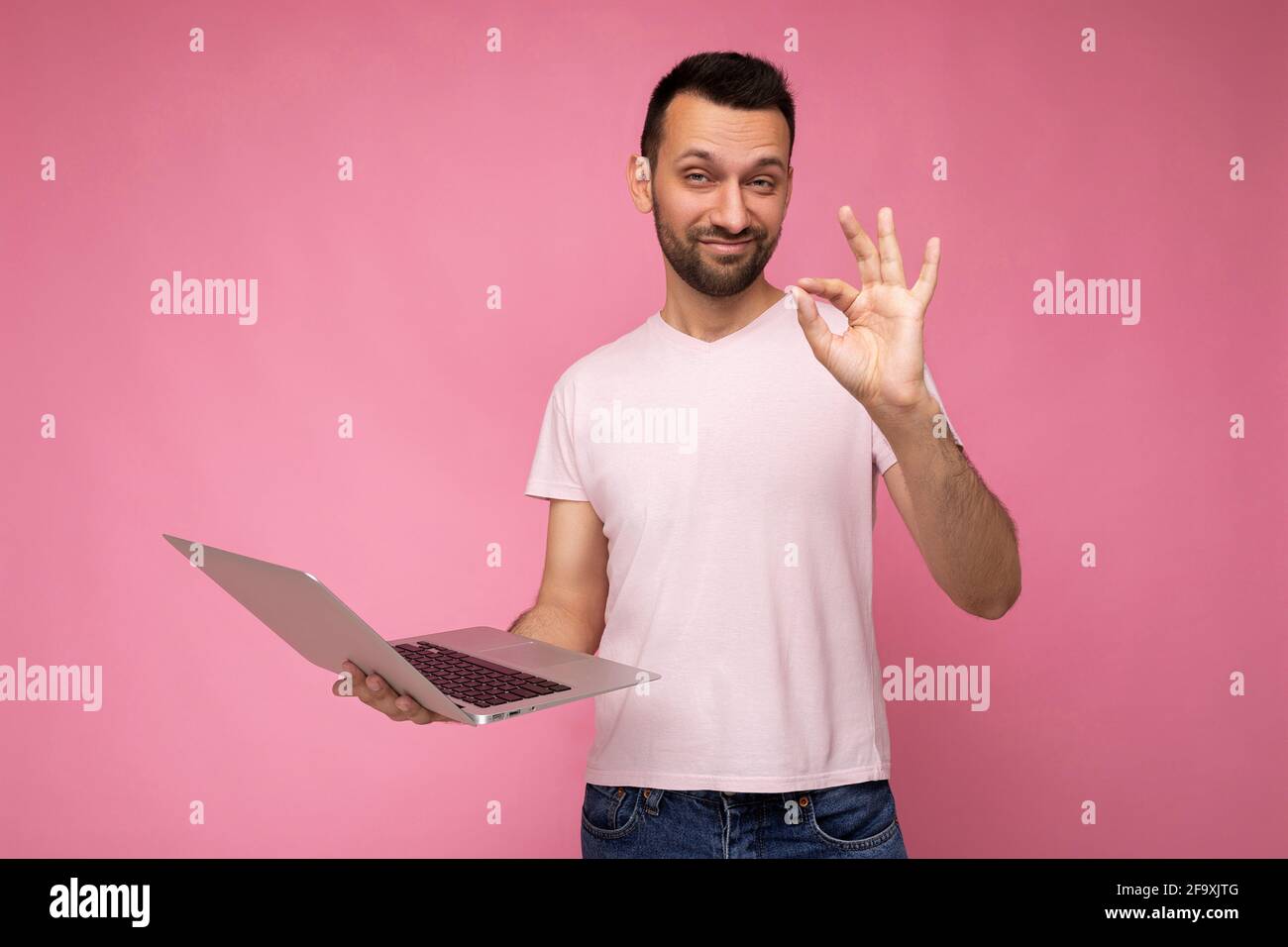 Handsome funny brunet man holding laptop computer and showing gesture ...
