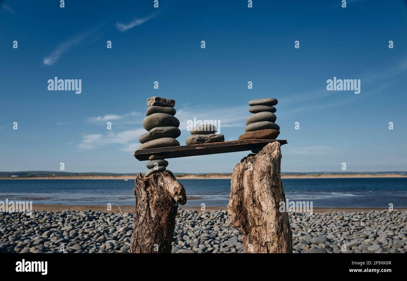 a beach sculpture of a tower of pebbles stacked on driftwood at ...