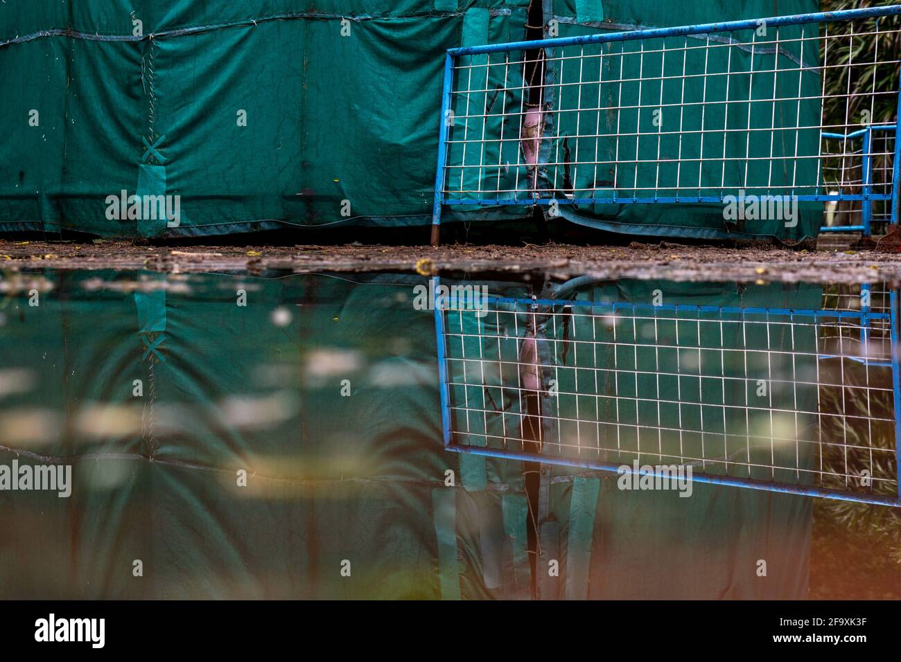 Closeup of the reflection of the metallic fence on the small puddle ...