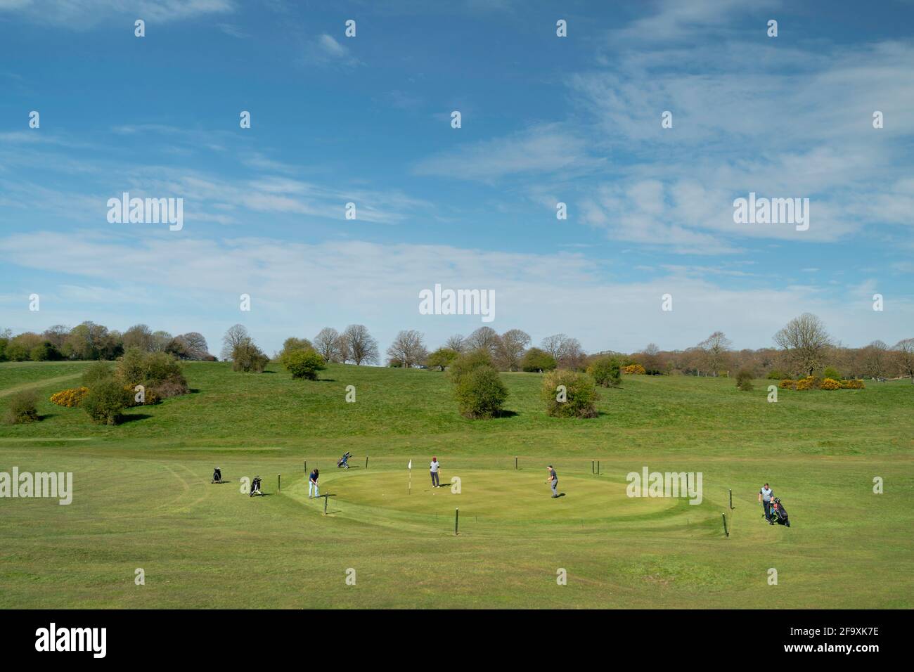 View across public parkland and golf course with golfers on bright ...