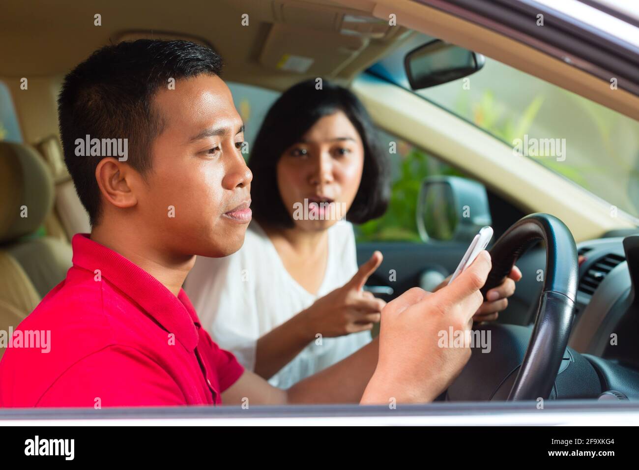 Asian man texting message and asian woman scolding Stock Photo - Alamy
