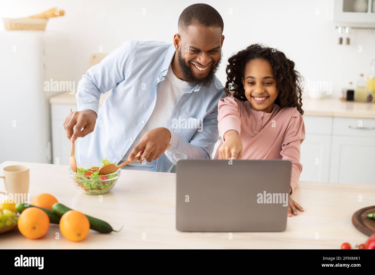 Black man and girl cooking in kitchen reading online recipe Stock Photo ...
